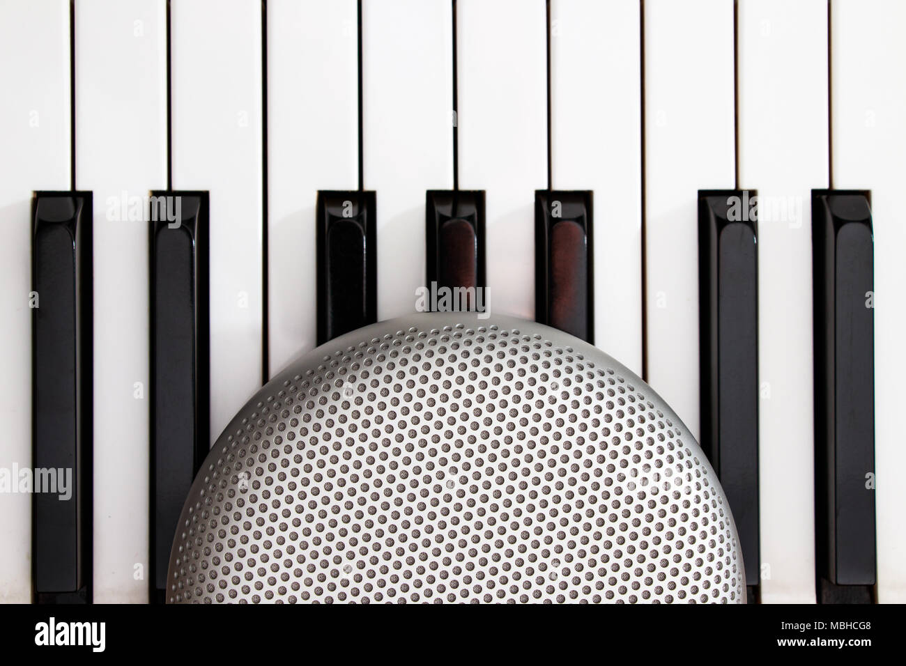 grey stylish speaker on the black and white piano keys on top view ...