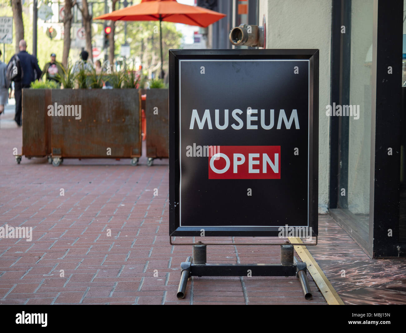 “Museum open” sign sitting outside building on a busy sidewalk during ...