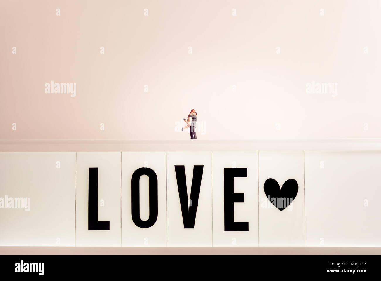 Loving couple hugging on top of a large LOVE sign Stock Photo - Alamy