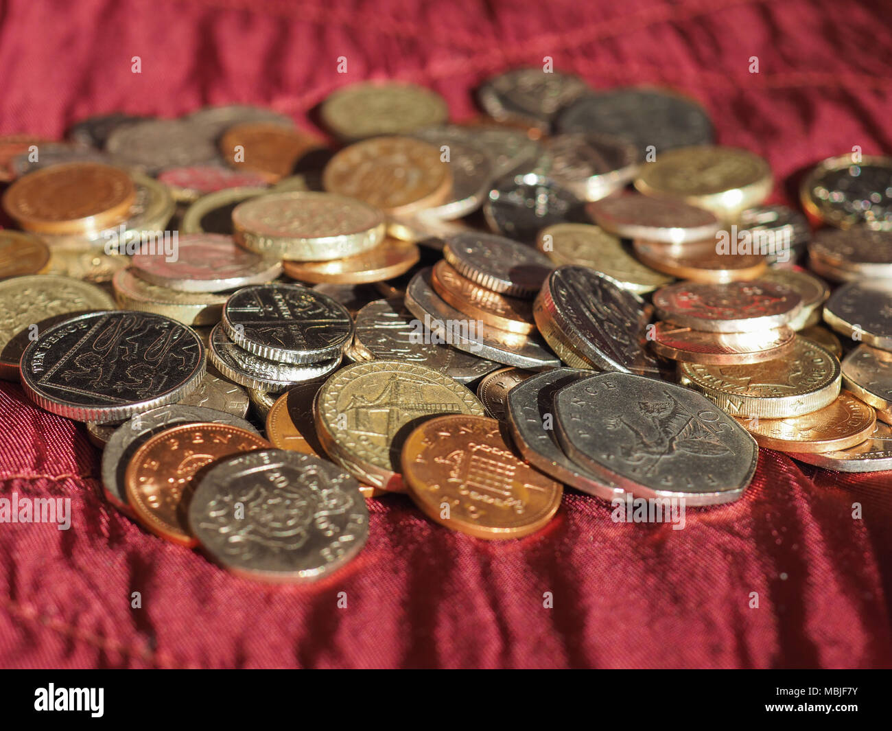 Pound coins money (GBP), currency of United Kingdom over crimson red ...