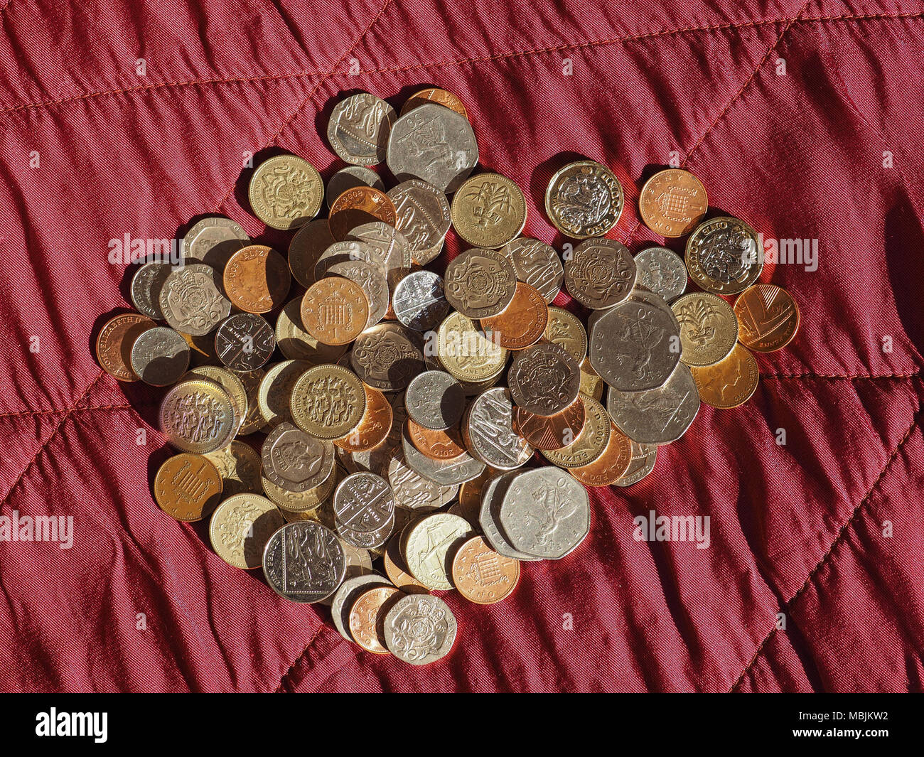 Pound coins money (GBP), currency of United Kingdom over crimson red ...