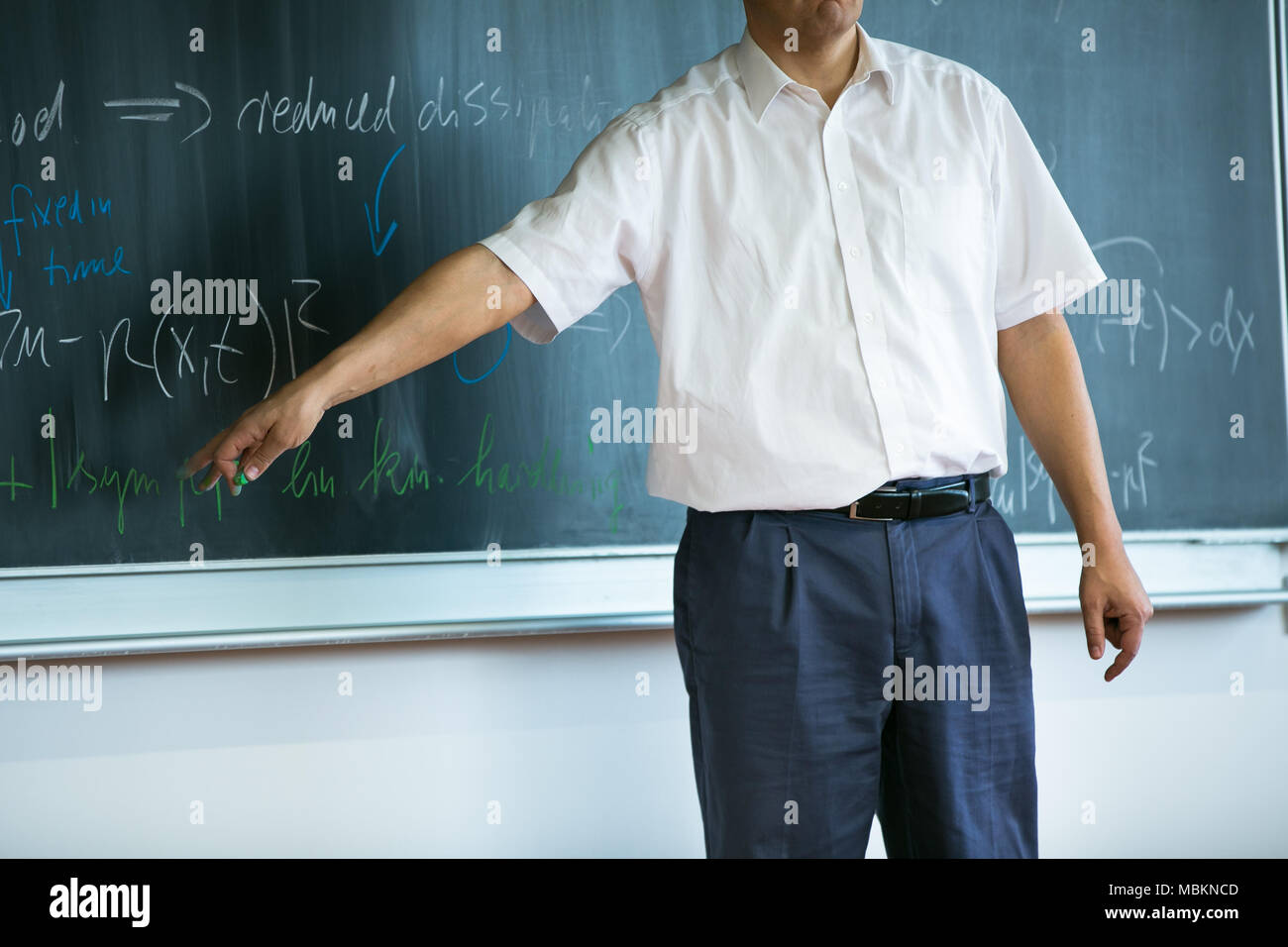 teacher teaching mathematics while pointing at blackboard in classroom ...