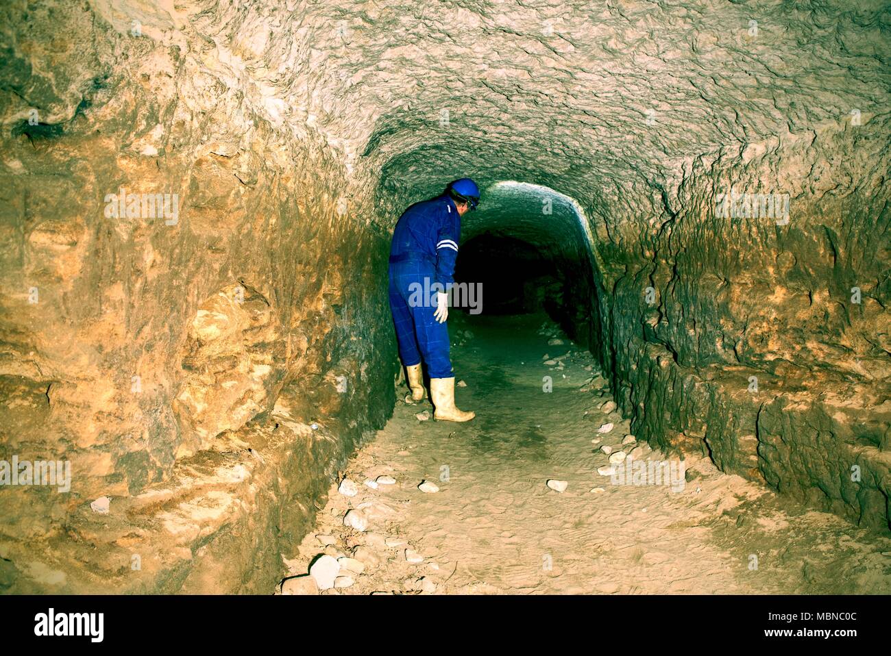 Man works in mystical ancient long tunnel from orange sandstone walls ...
