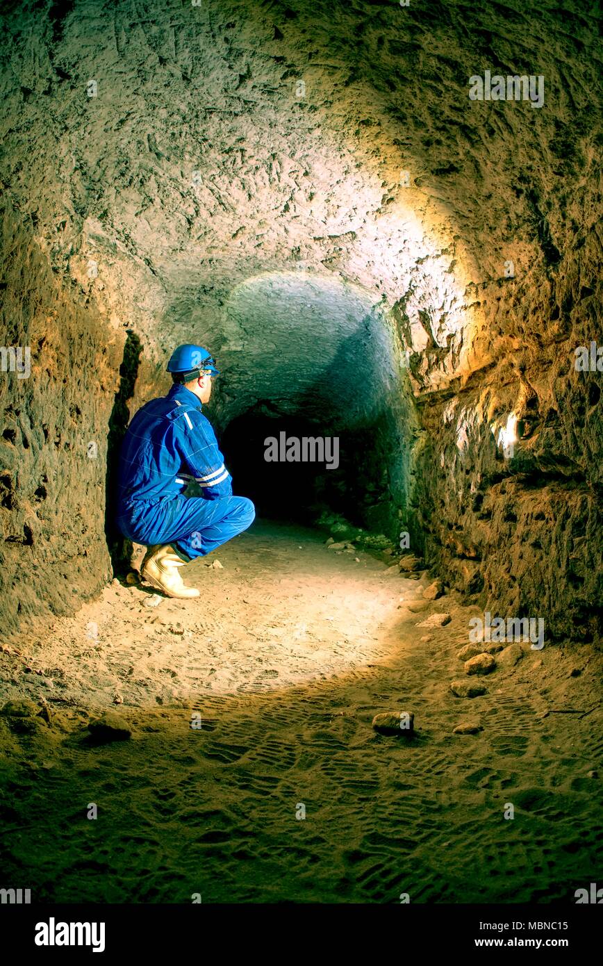 Workerman with helmet and protective suit using glowes and head lamp ...