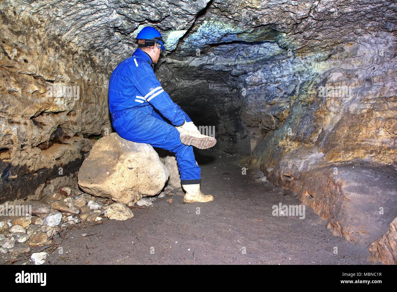 Miner man underground in a mine tunnel. Worker in overalls, safety ...