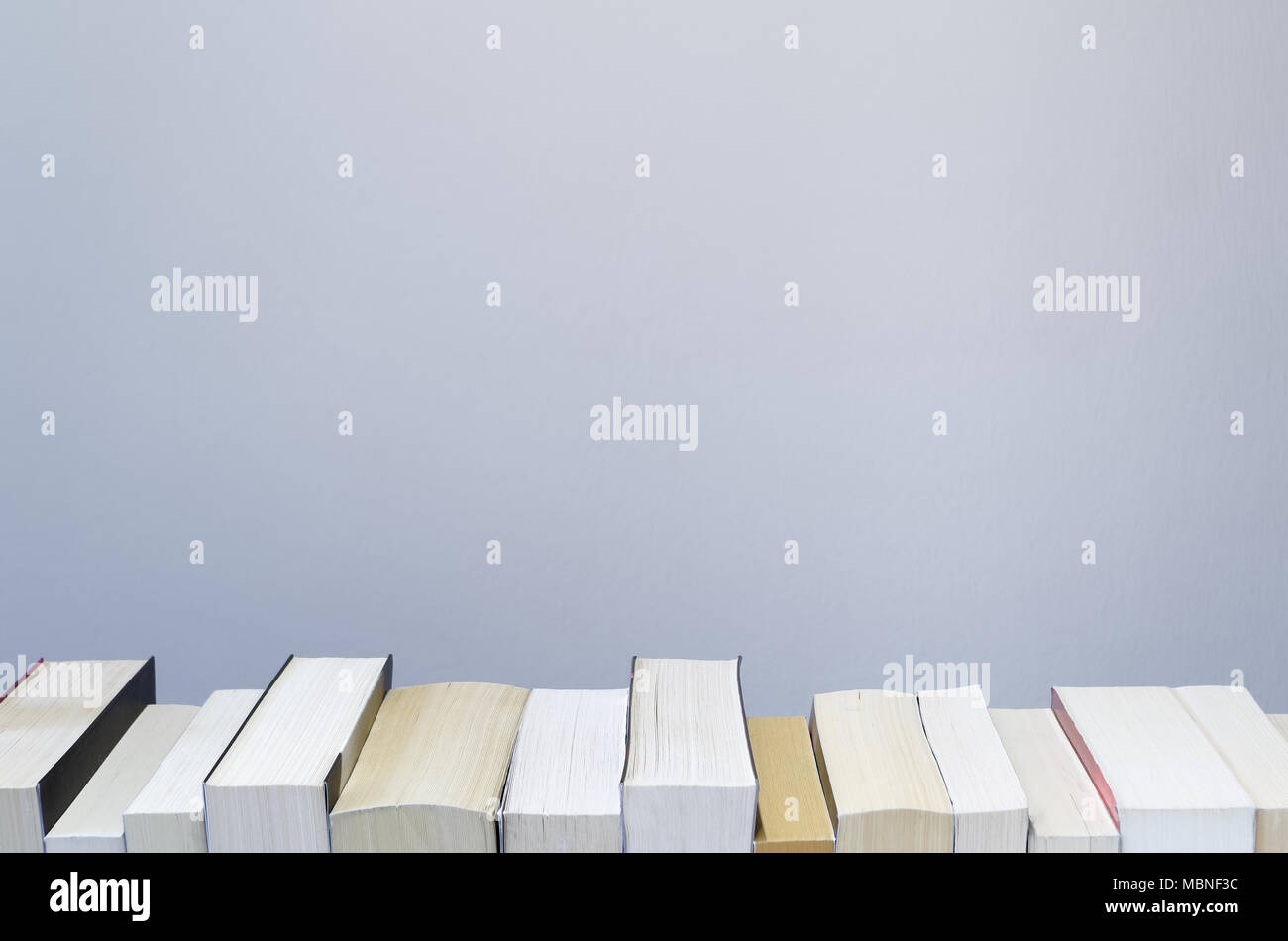 Books in a row on light grey background Stock Photo - Alamy