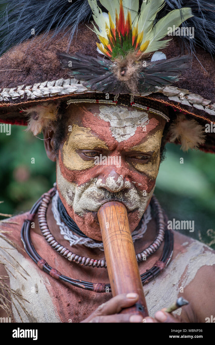 A Huli wigman with painted face smokes from a bamboo pipe, Tari Valley ...