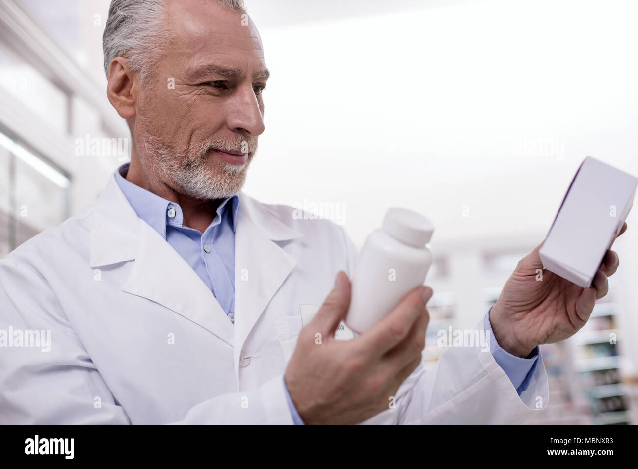 Reflective male pharmacist verifying drugs Stock Photo - Alamy