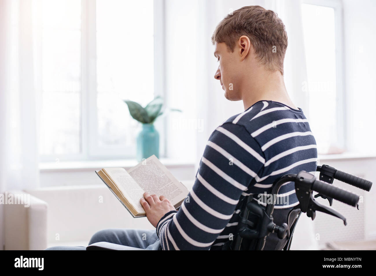 Relaxed young man reading book Stock Photo - Alamy