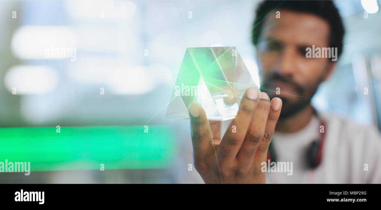 Close up innovative male entrepreneur examining glass triangle ...