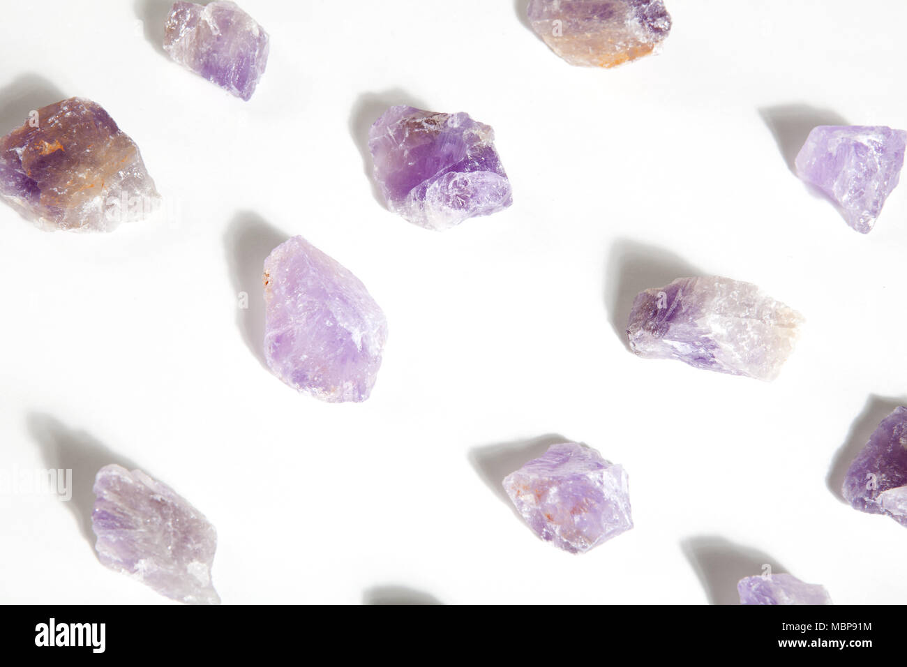 several pieces of raw amethyst lined up on a white background. Minimal ...