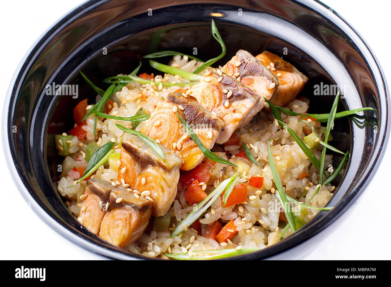 Japanese food. Rice with vegetables and fried salmon in a black bowl ...