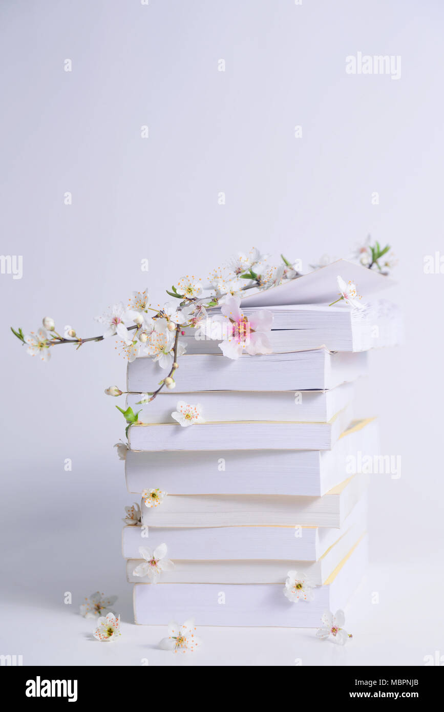 Stack of books with spring flowers between pages on a white background ...