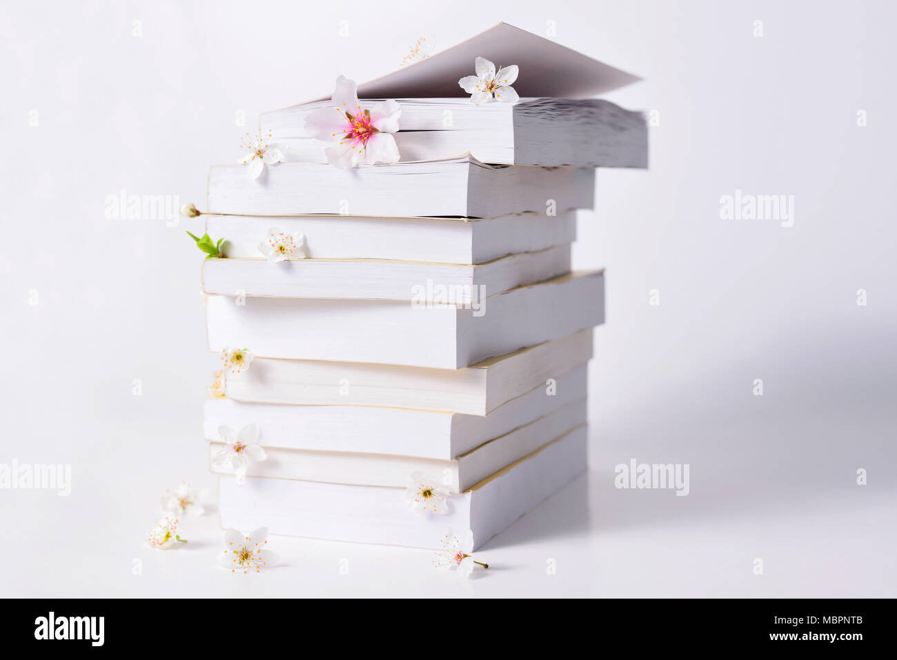 Stack of books with spring flowers between pages on a white background ...