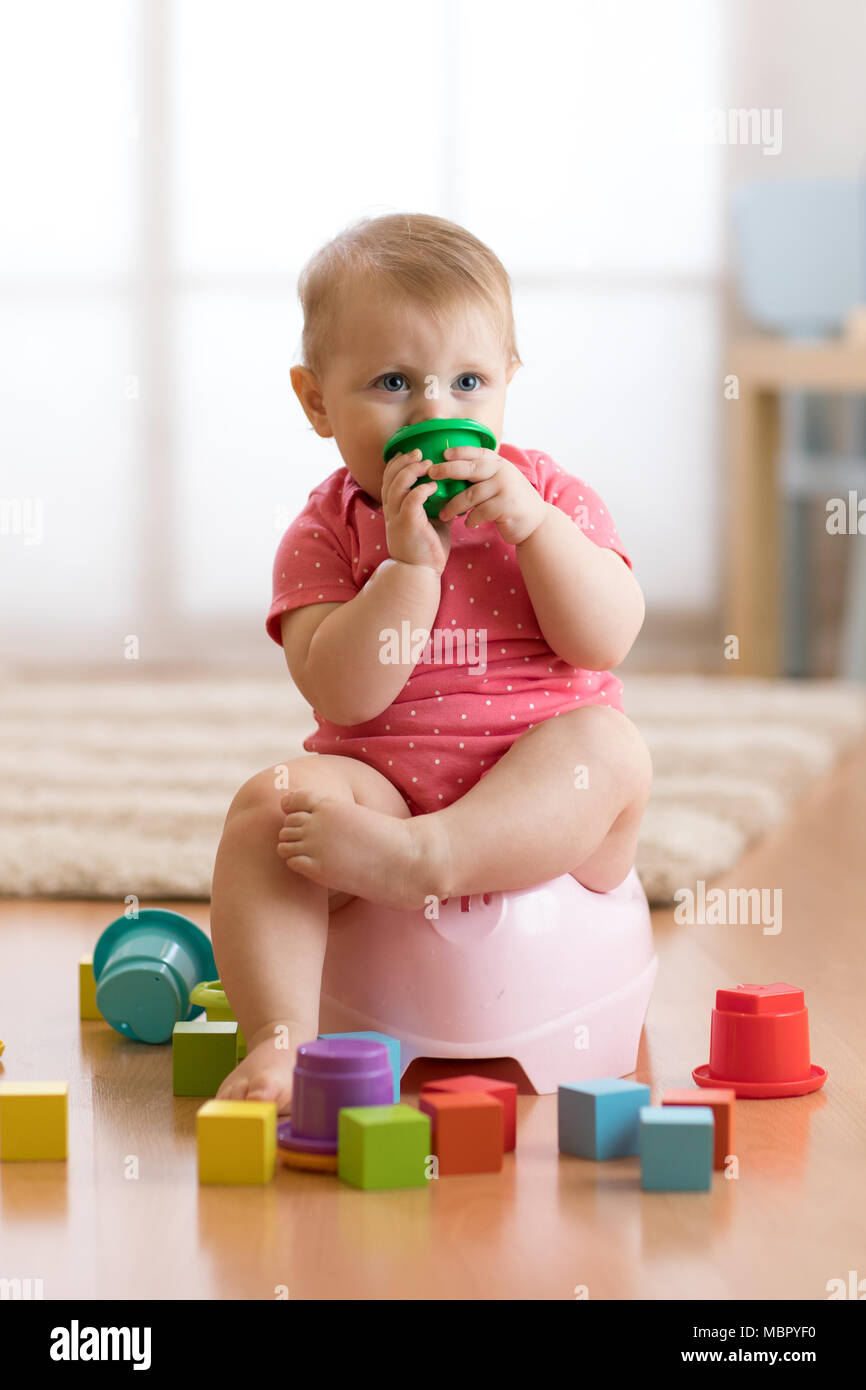 baby sits on a children's pot, toilet, playing with toys Stock Photo ...
