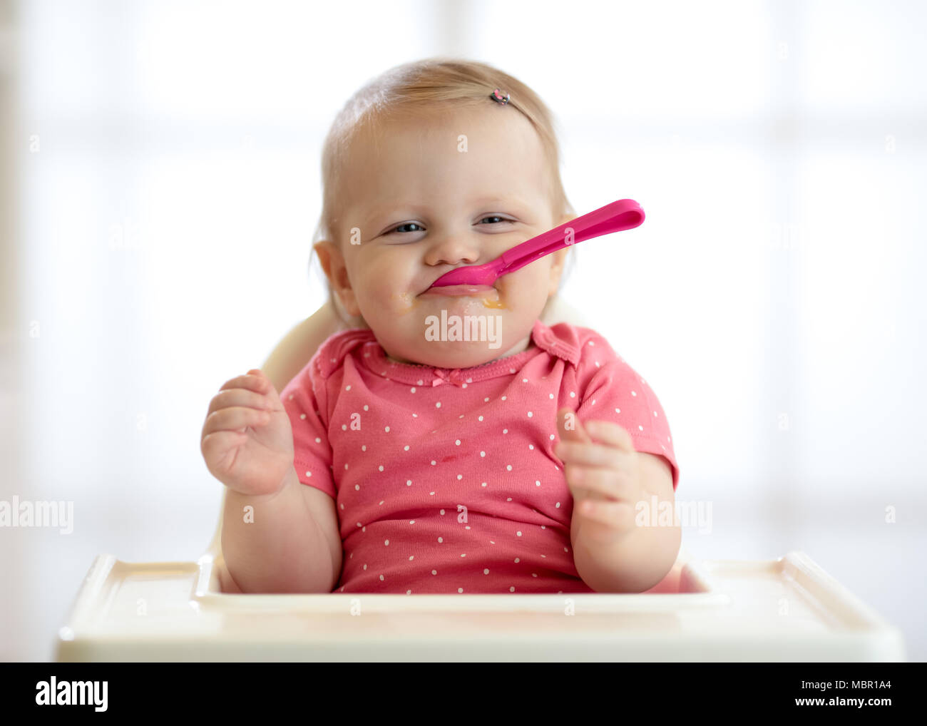 funny baby girl eating food on kitchen Stock Photo - Alamy