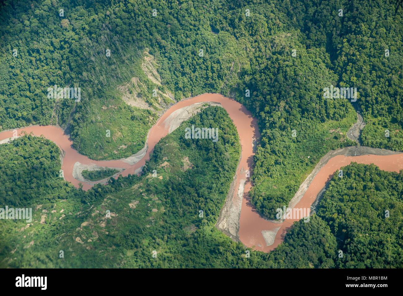 Aerial view of a river with pink waters caused by gold mining pollution ...