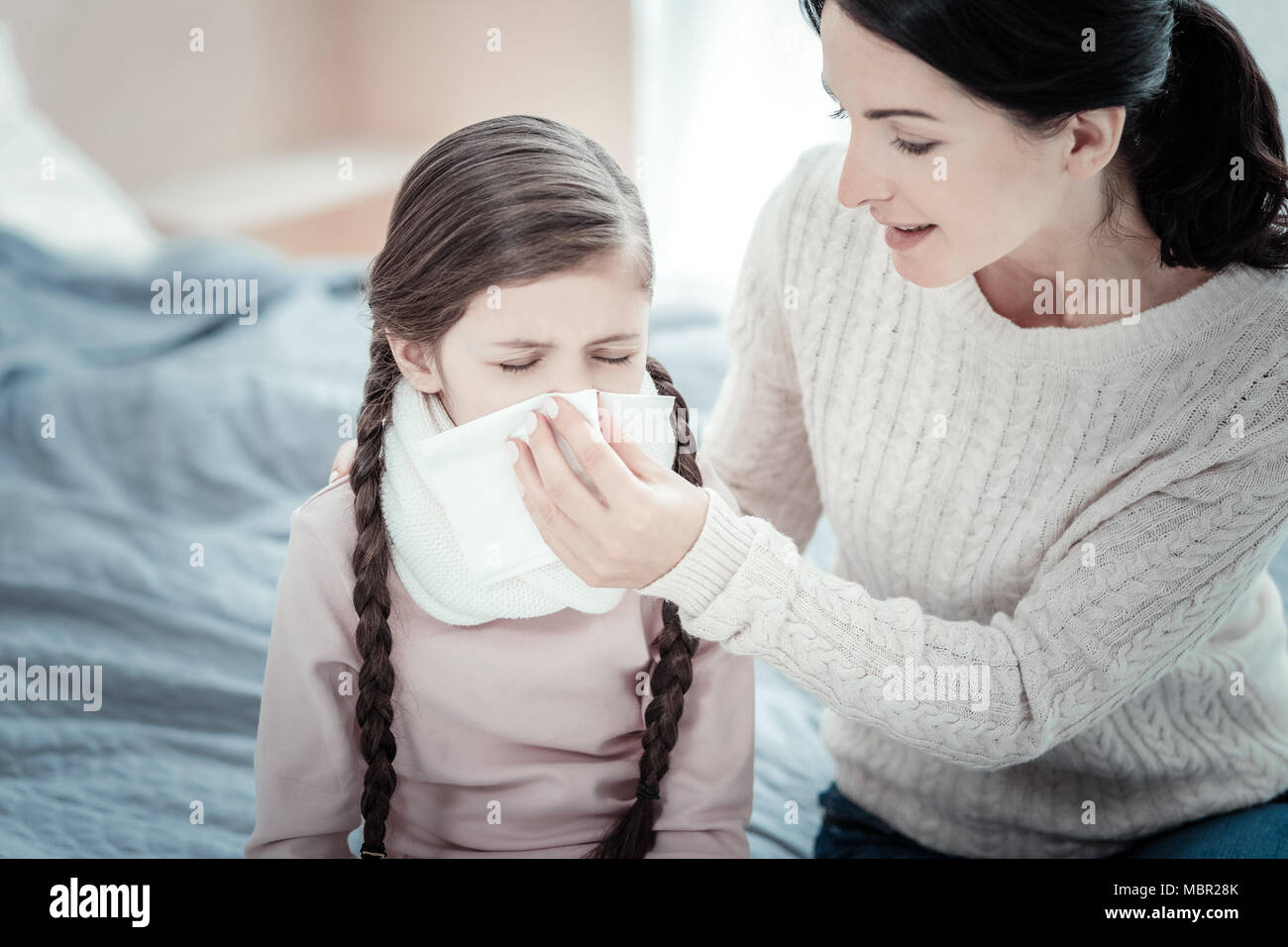 Caring lovely mother sitting and taking care of her daughter Stock ...