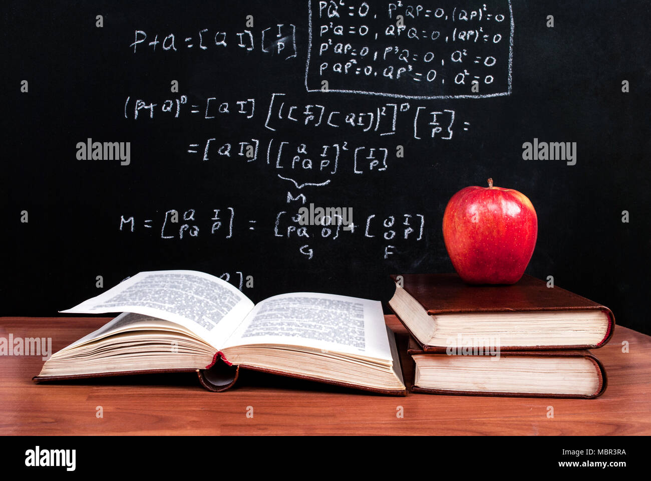 Apple and books on a wooden table and school blackboard with ...