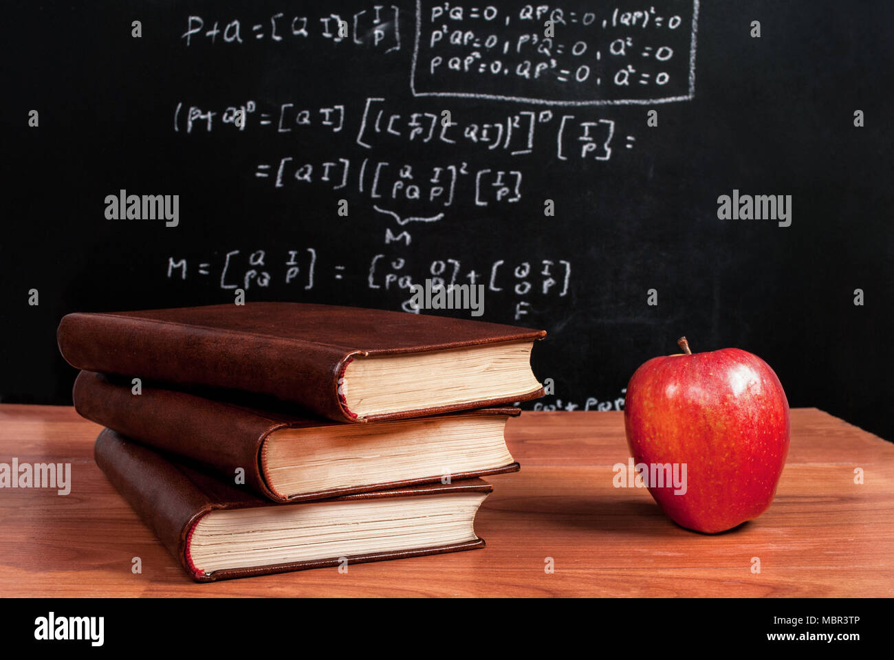 Books and red apple on a wooden table in math class in the classroom ...