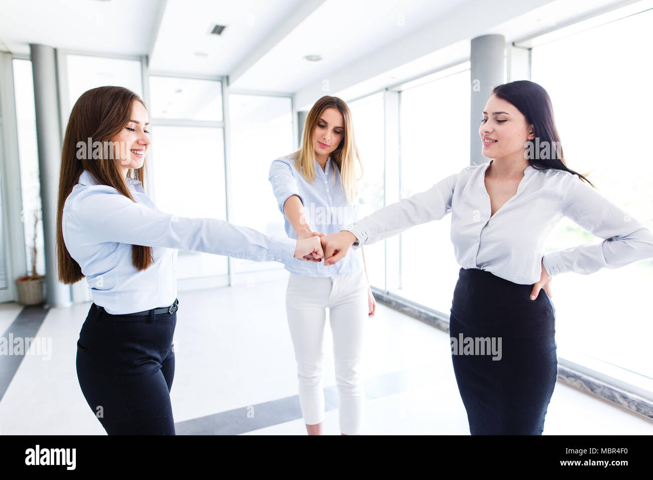 Three successful women celebrate their success by getting their hands ...