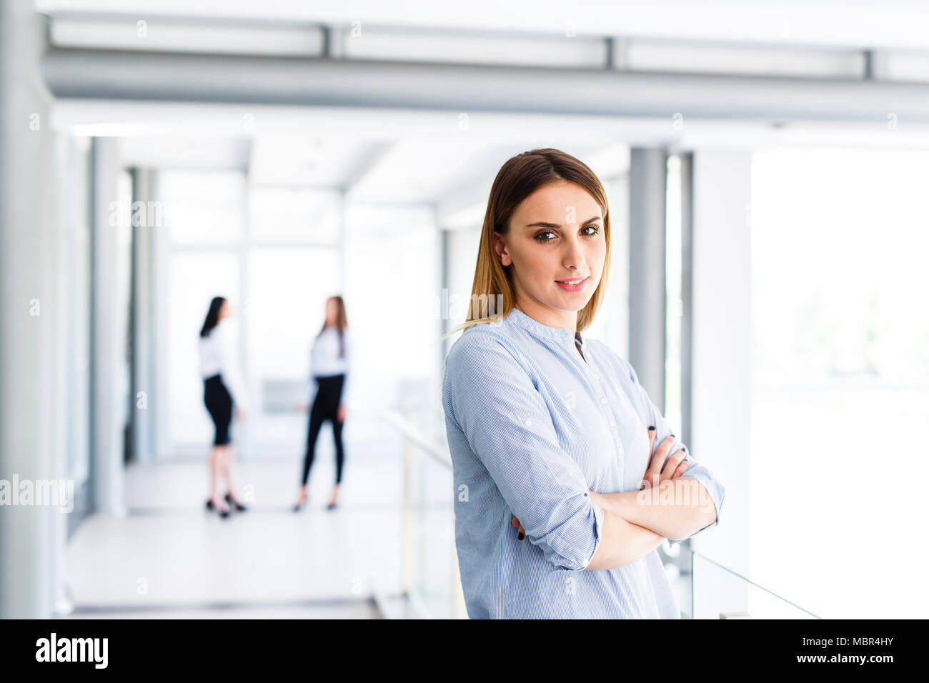 Beautiful businesswoman posing at workplace in front of her colleagues ...