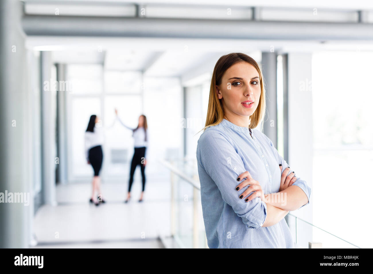 Beautiful businesswoman posing at workplace in front of her colleagues ...