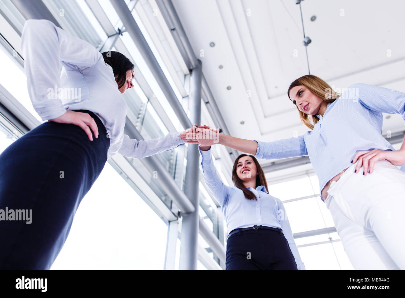 Three successful women celebrate their success by getting their hands ...