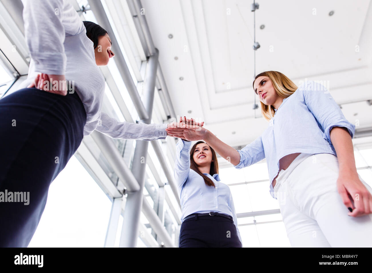 Three successful women celebrate their success by getting their hands ...