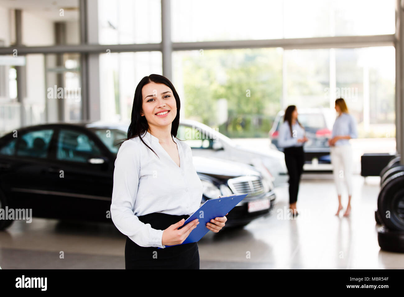 Business woman standing in car dealership with her work colleague in ...