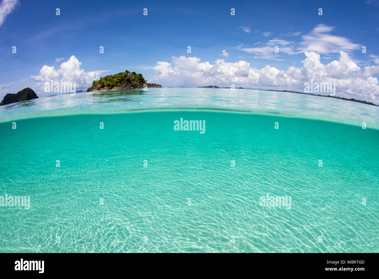 Clear, warm water covers a shallow sand flat near Misool, Raja Ampat ...