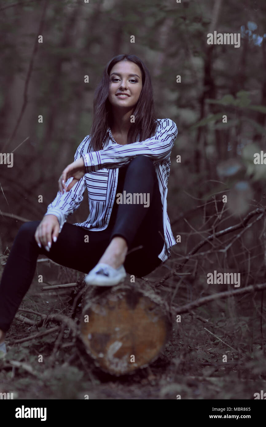 beautiful young woman sitting on a log Stock Photo - Alamy