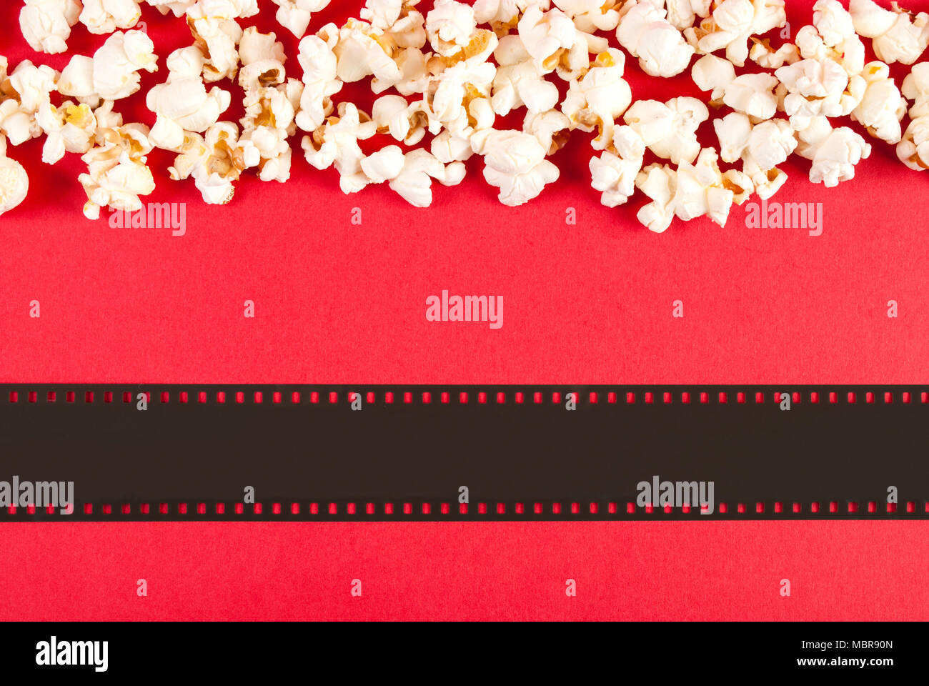 Close up popcorn and film tape on red background, top view and space ...
