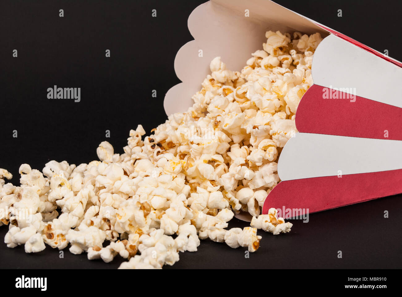 Close up spilled popcorn and box on black background Stock Photo - Alamy