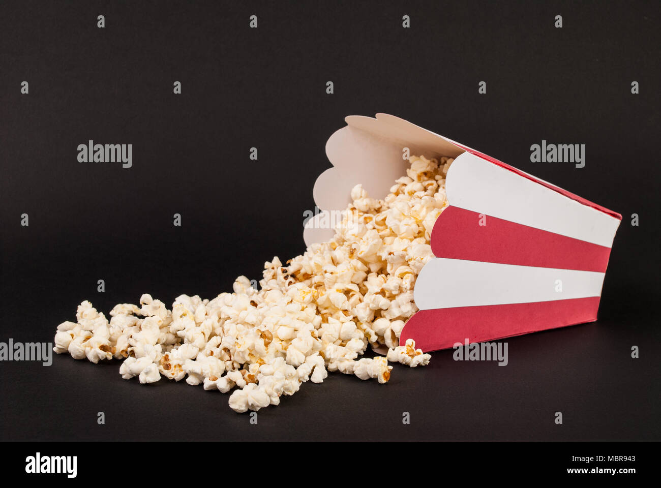 Popcorn spilled of box on black background Stock Photo - Alamy