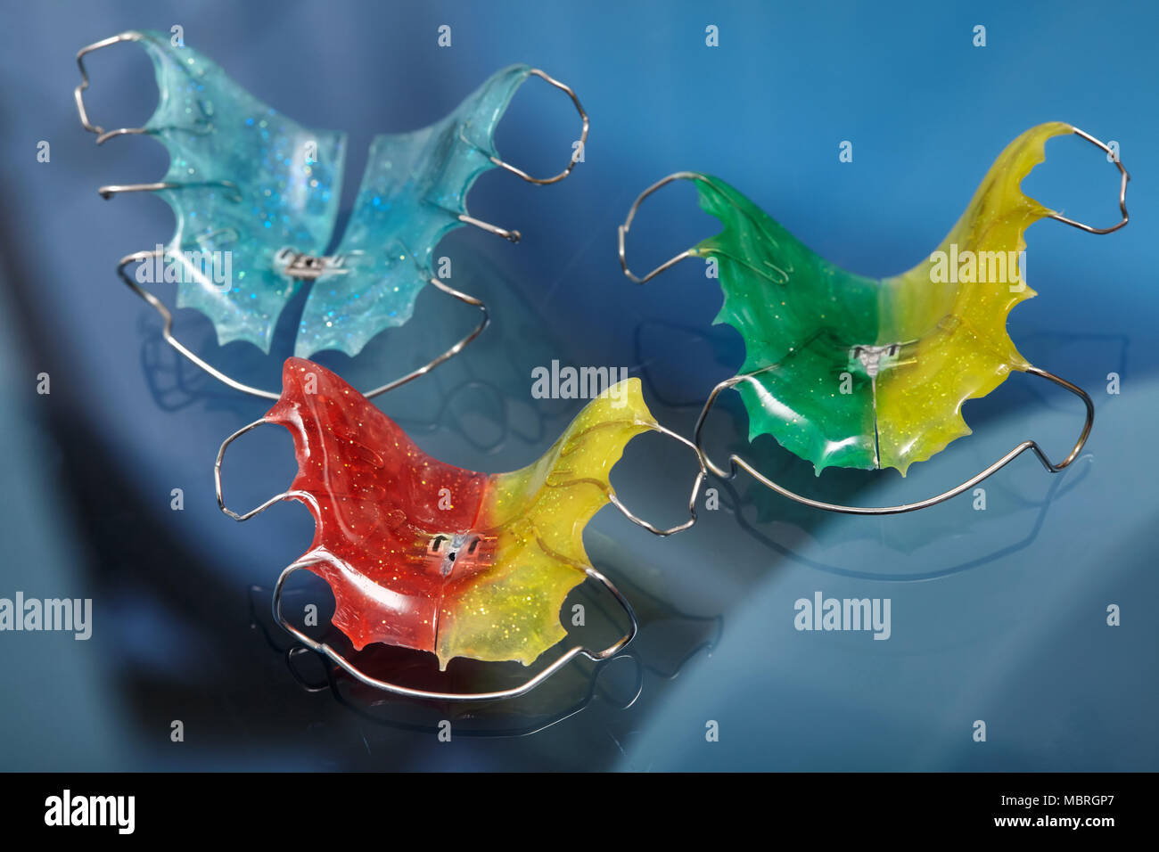 Colorful dental braces or retainers for teeth on blue glass background ...