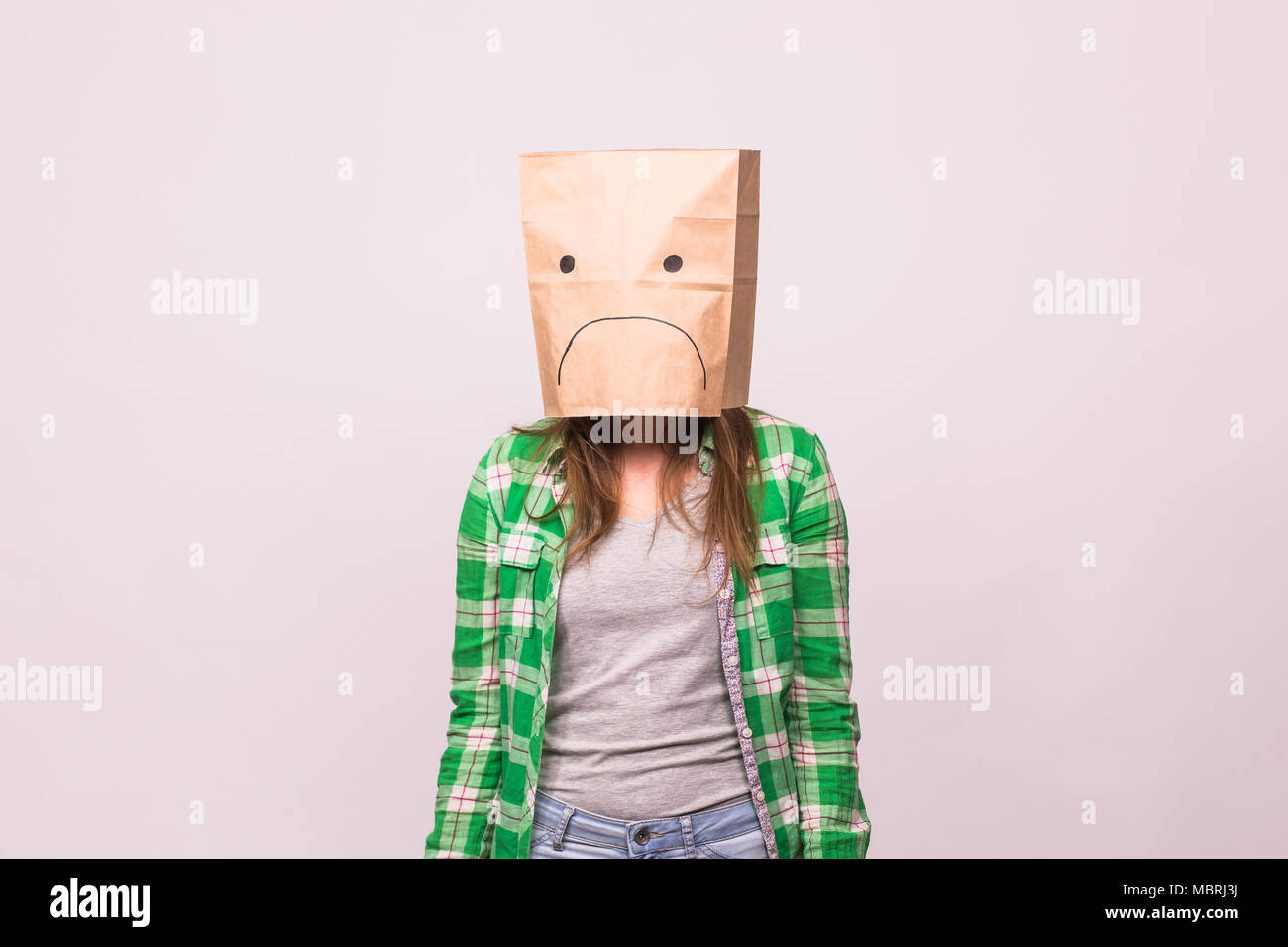 Unhappy girl with sad emoticon on paper bag on her head on white ...