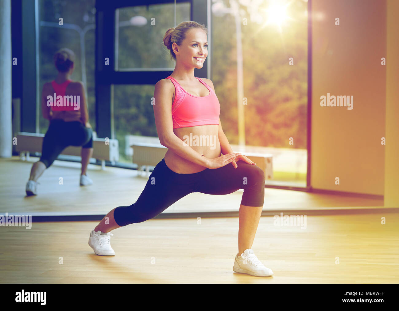 smiling woman stretching leg in gym Stock Photo - Alamy