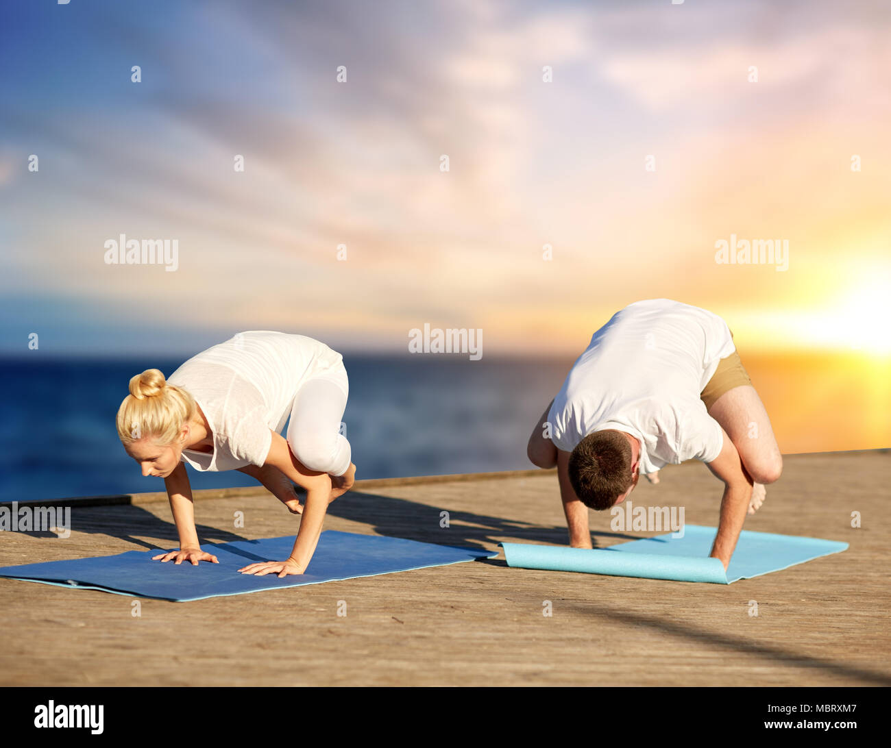couple doing yoga crow pose outdoors Stock Photo - Alamy
