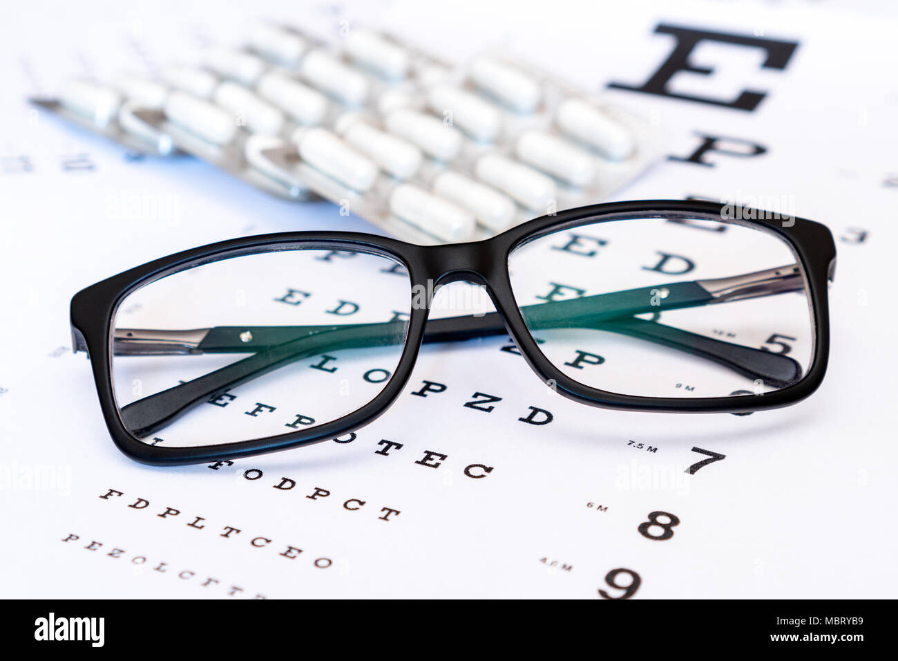Black glasses and blister of tablets on the eye exam chart Stock Photo ...