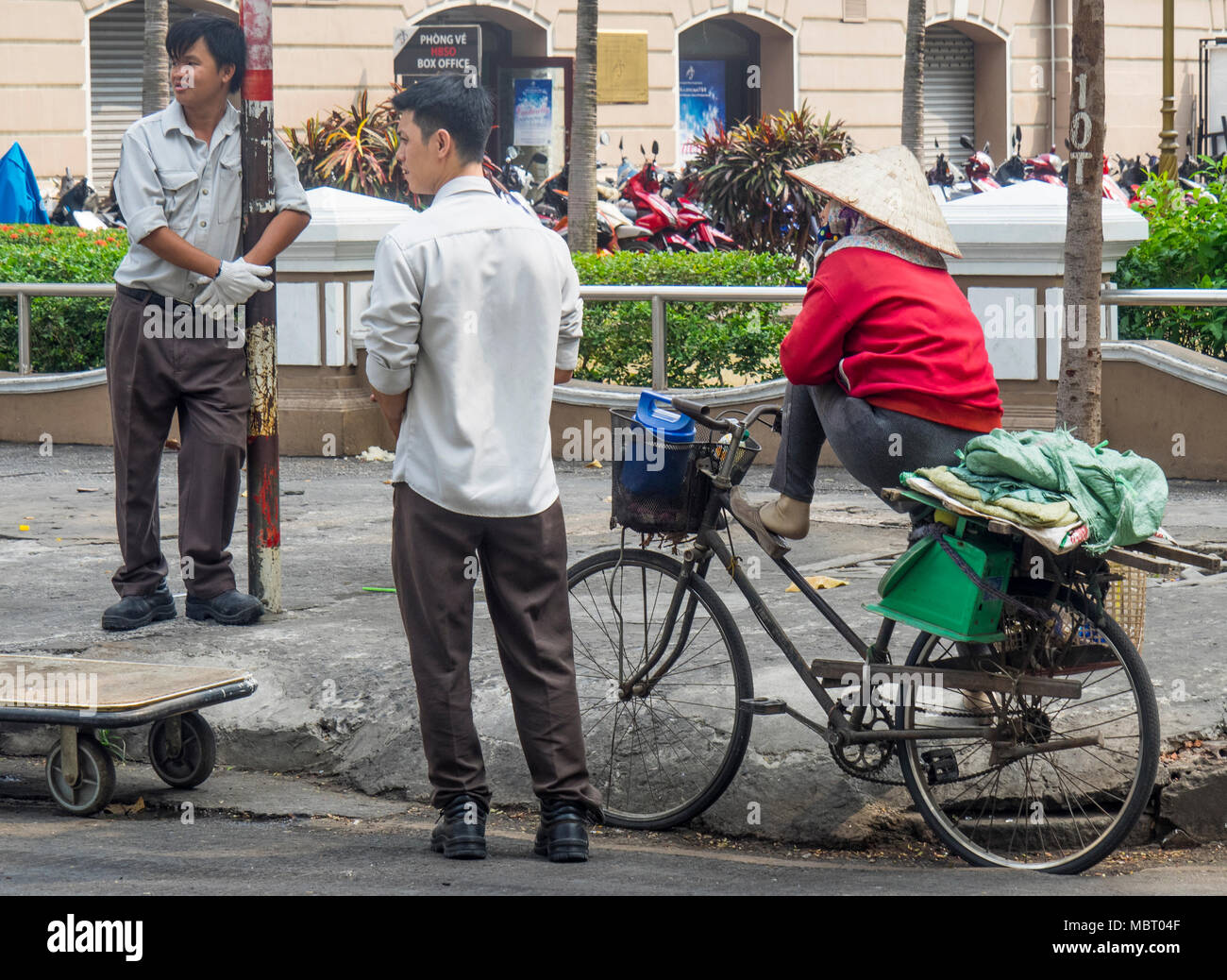 A Vietnamese woman with a bicycle and wearing a conical straw hat ...