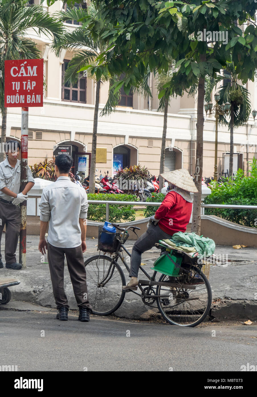 A Vietnamese woman with a bicycle and wearing a conical straw hat ...