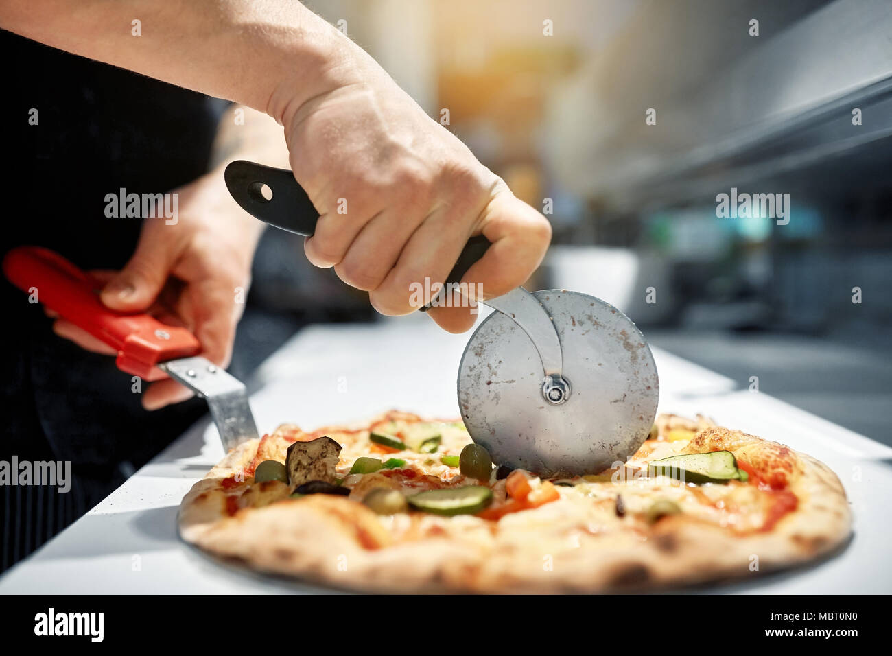 cook cutting pizza to pieces at pizzeria Stock Photo - Alamy