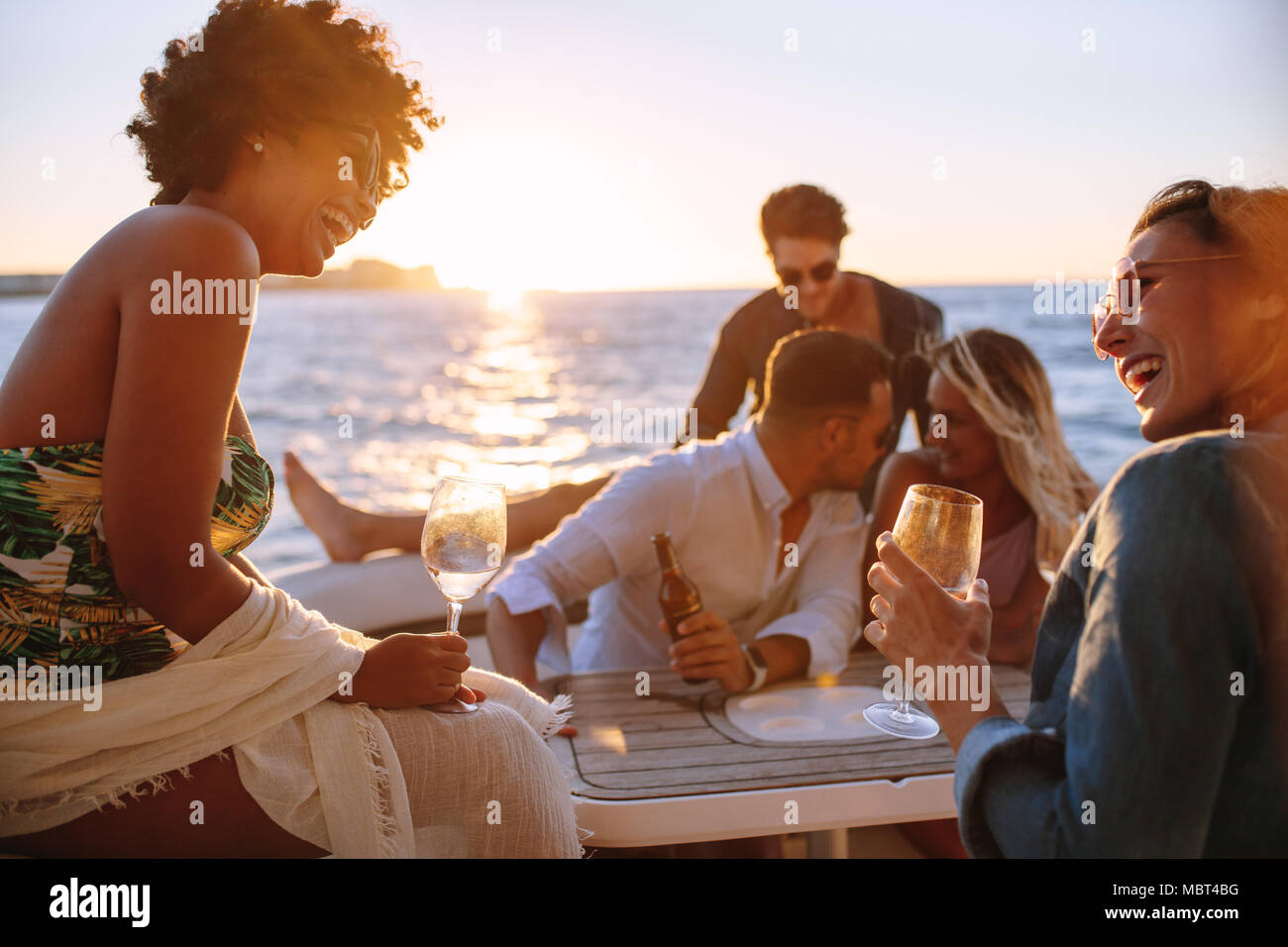 Group of men and women having a boat party during sunset. Happy young ...
