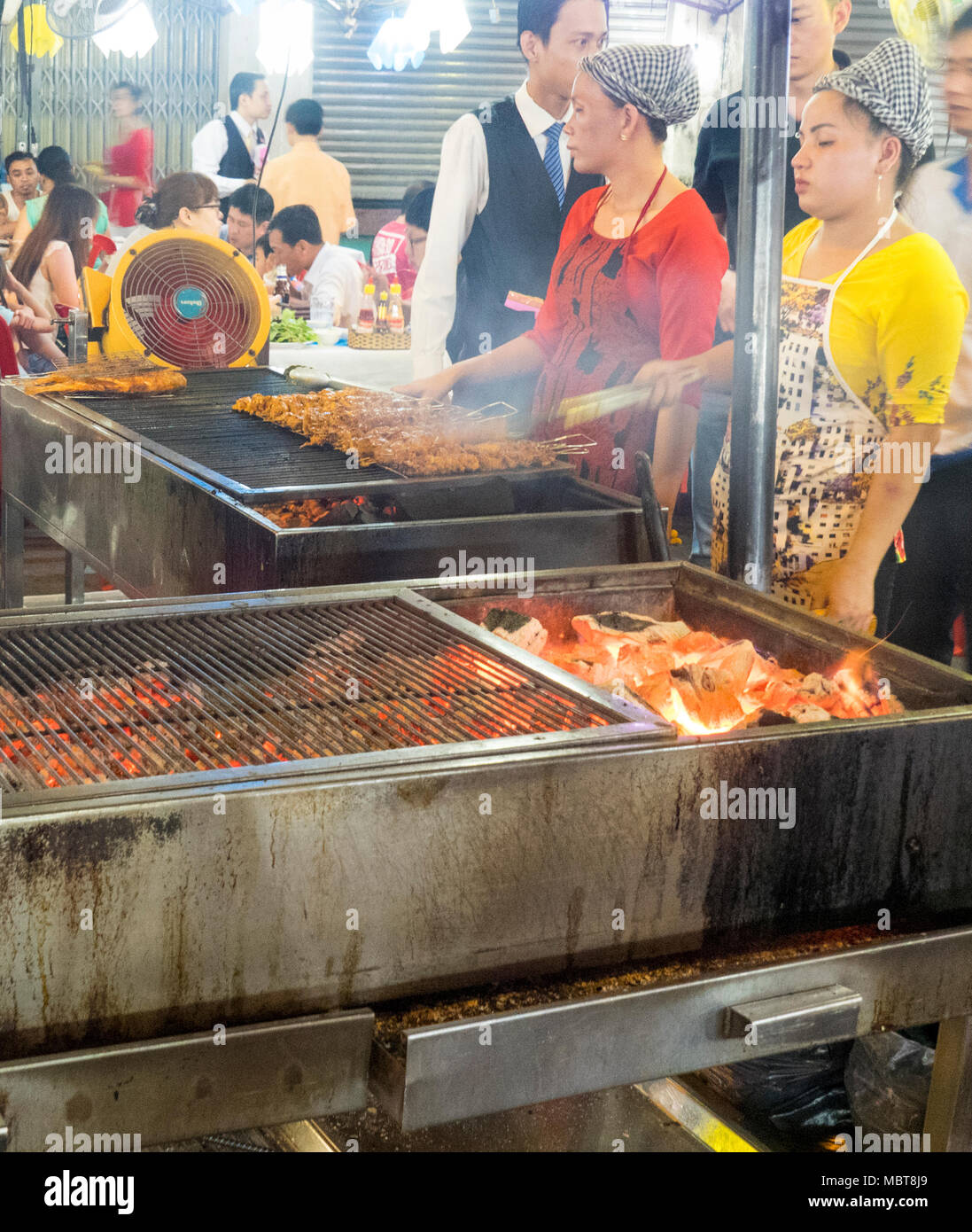 Women barbecuing seafood at a seafood restaurant at the night markets ...