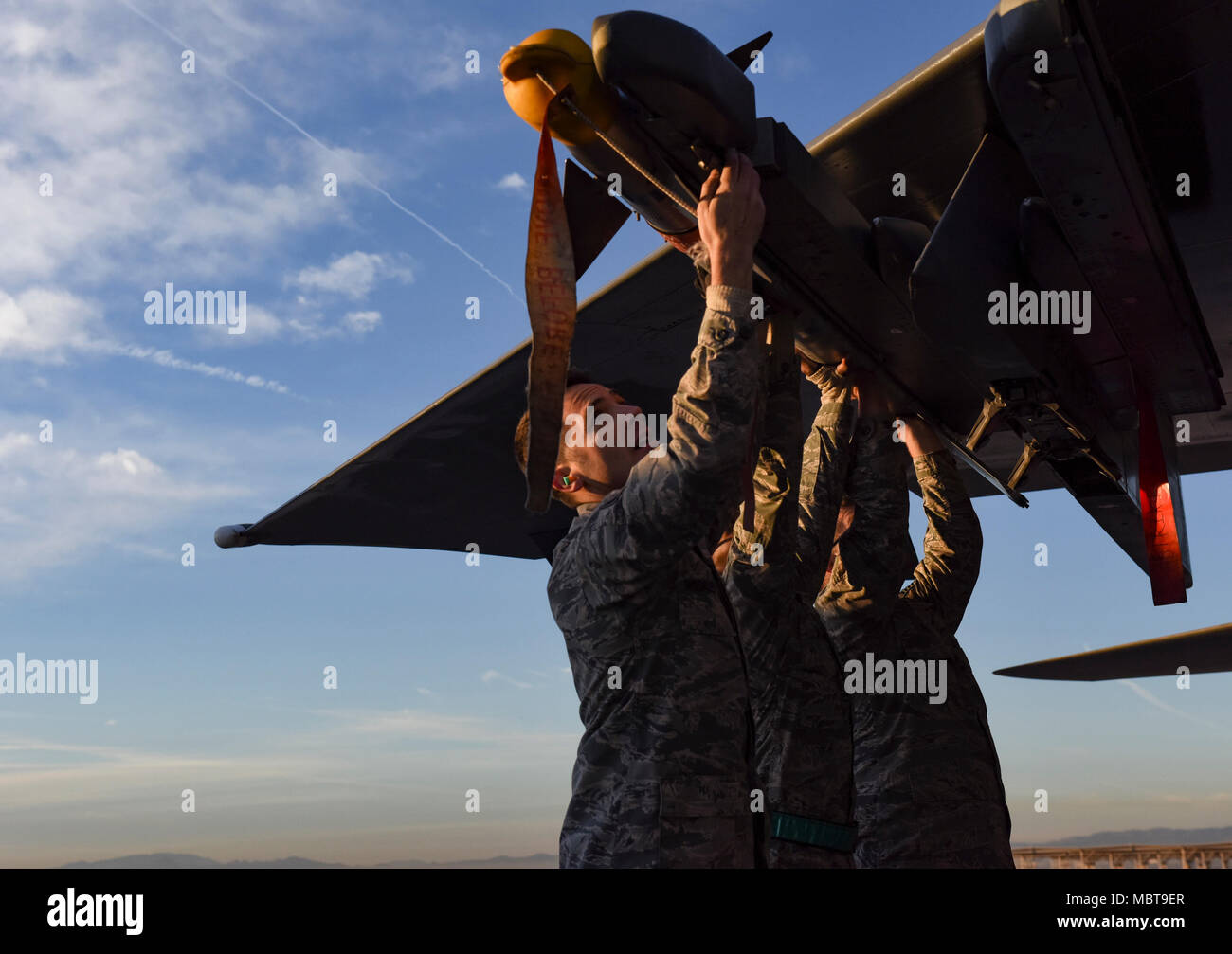 Airmen from the 57th Maintenance Group load an AIM-120 AMRAAM onto an F ...