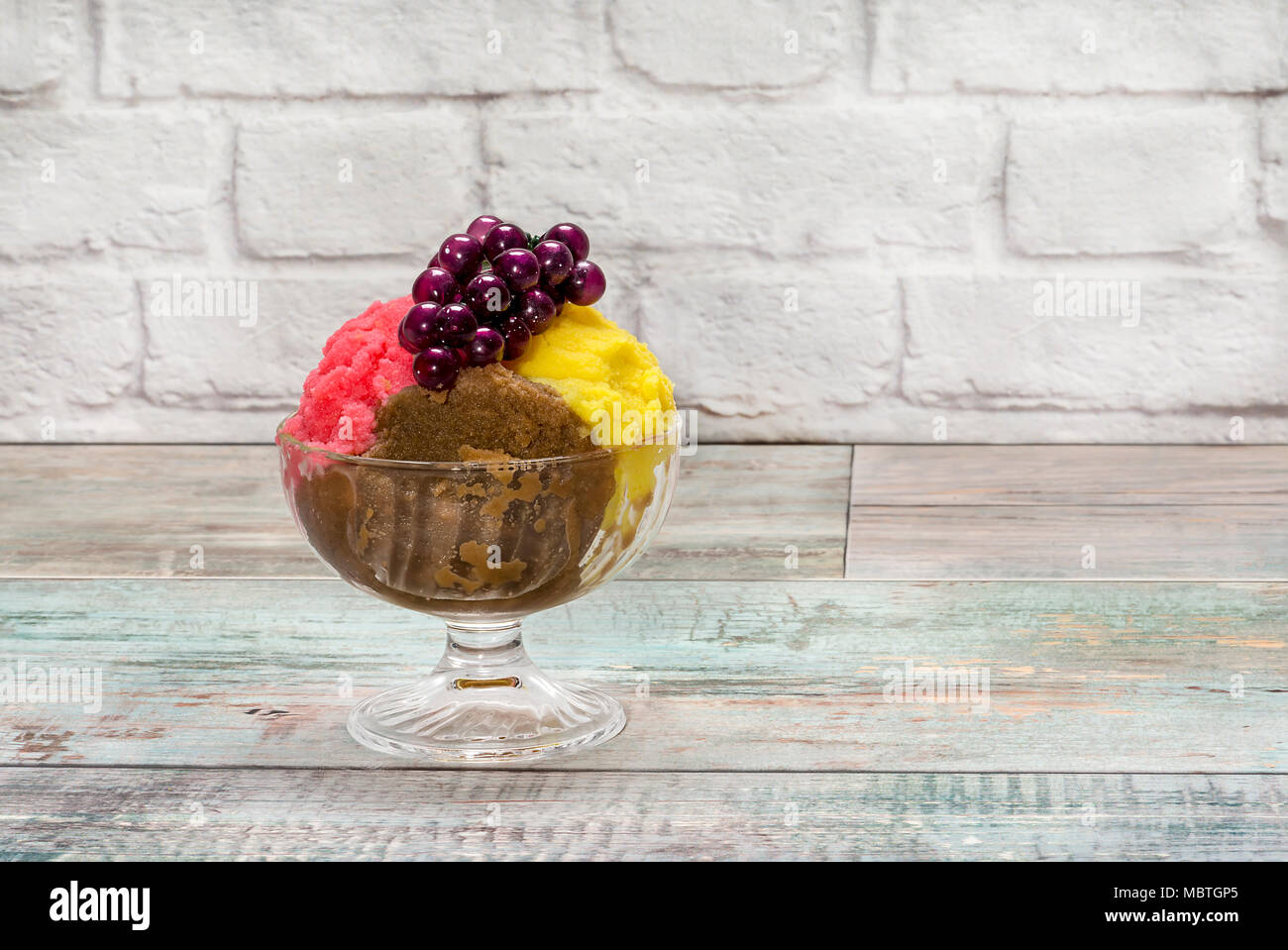 glass with three different flavors of ice cream with a bunch of grapes ...