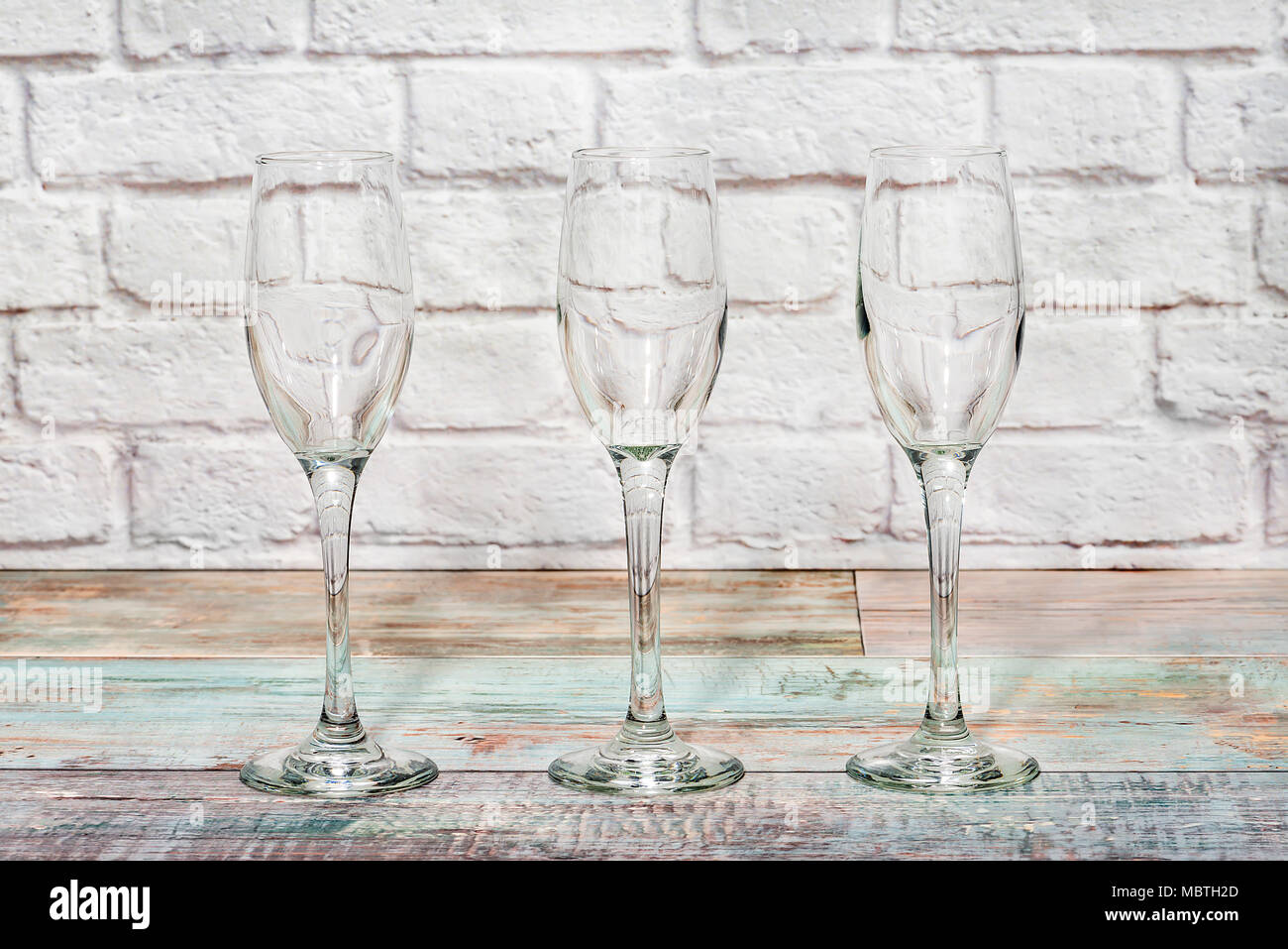 Three empty glass goblets on a rustic table with white bricks on ...