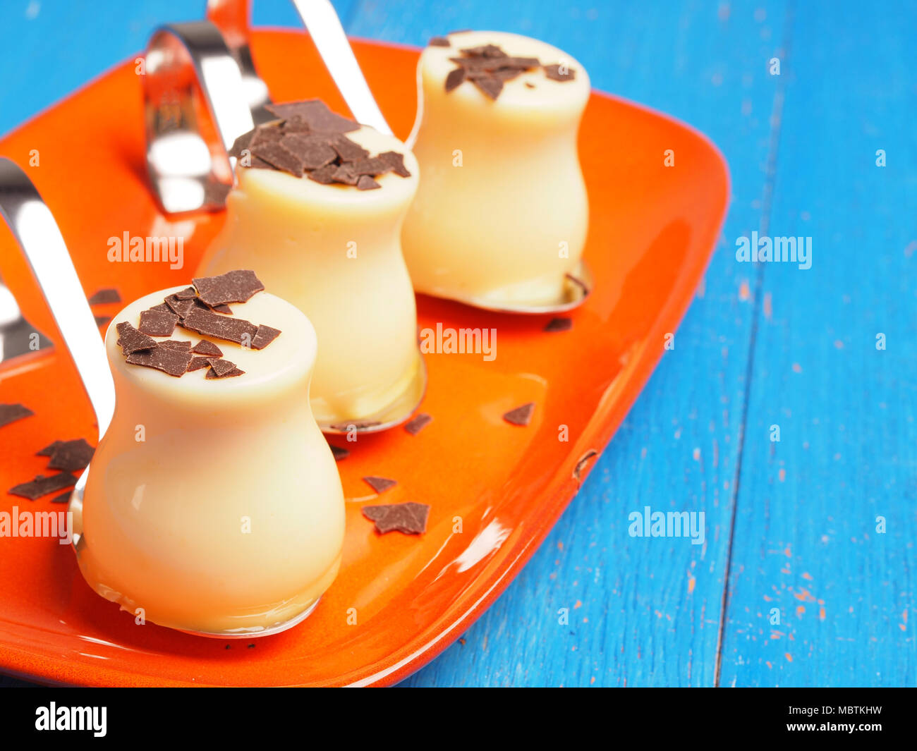 Tasty sweet vanilla pudding with chocolate flakes on an orange plate ...
