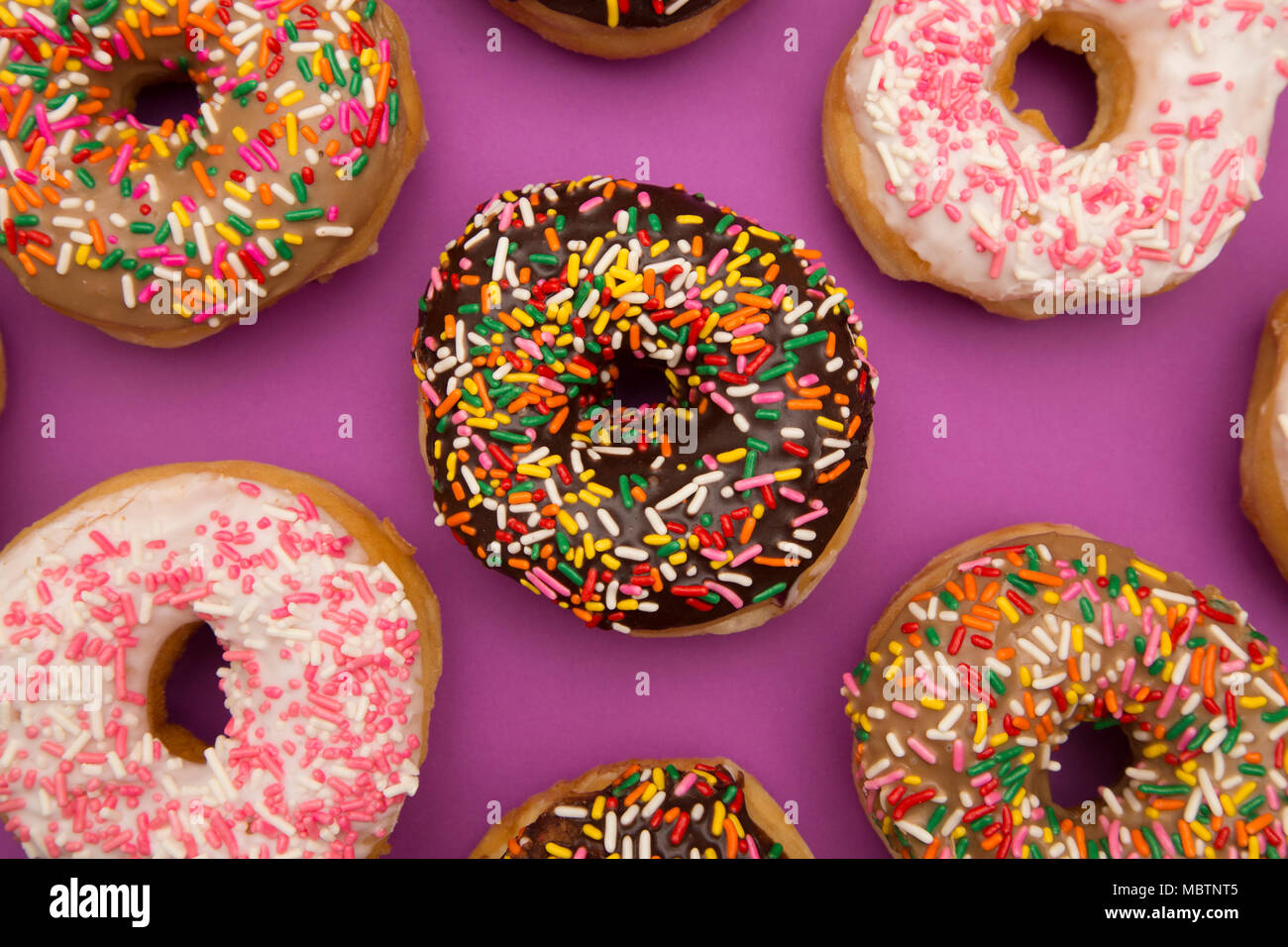 A Background of Various Sprinkle Donuts on a Purple Background Stock ...